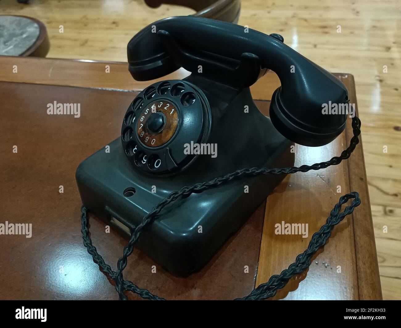 Black antique analog telephone dialing phone on wooden desk. Vintage ...