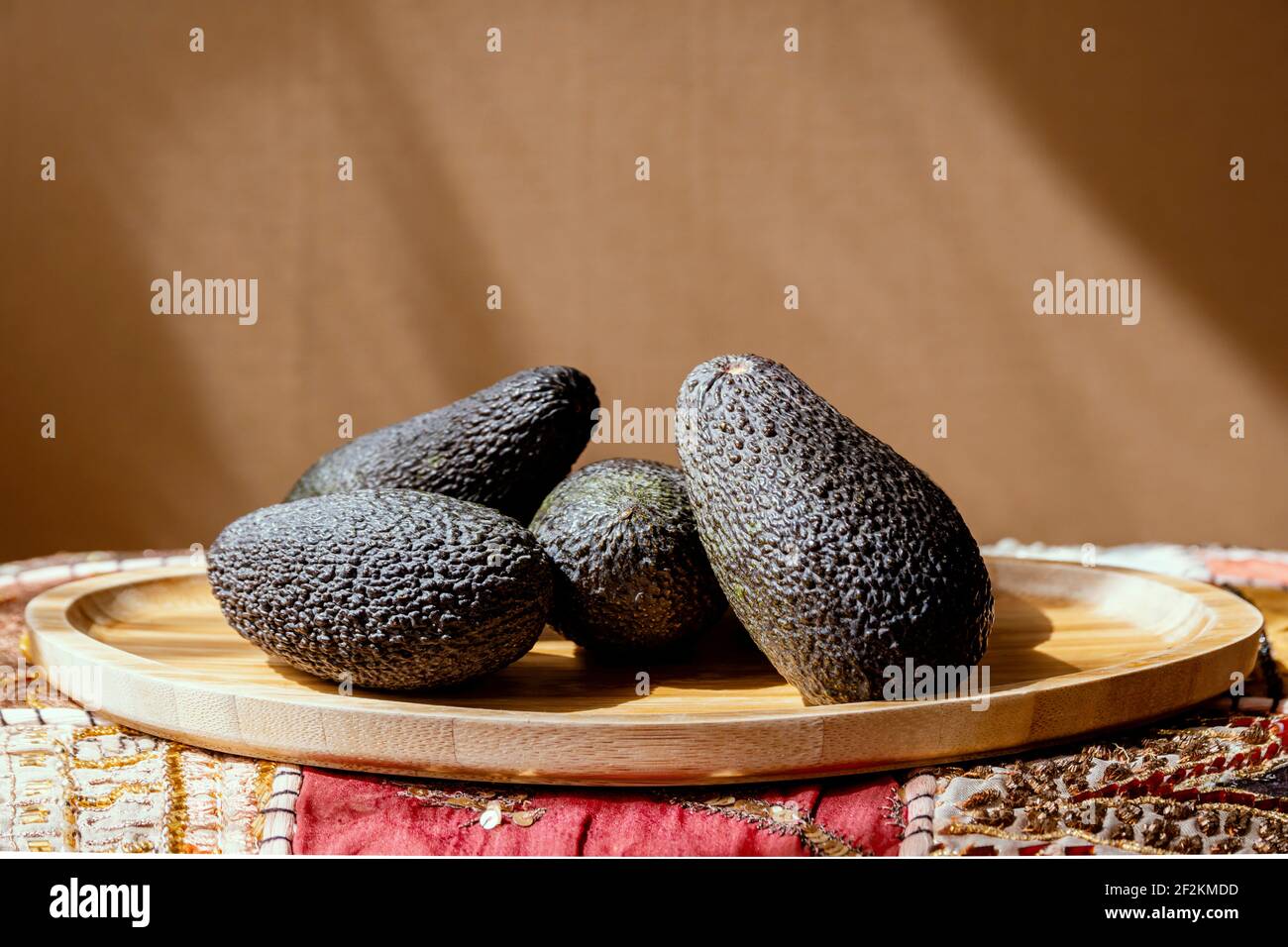 Many uncut avocado on wood board at sun light with copy space and ...