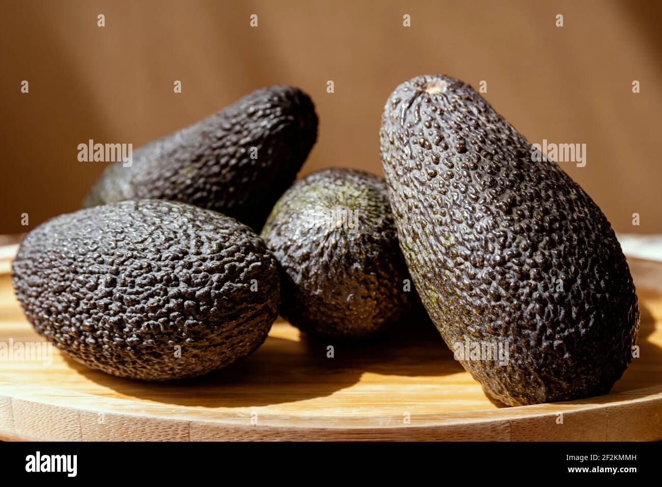 Many uncut avocado on wood board at sun light with copy space and ...