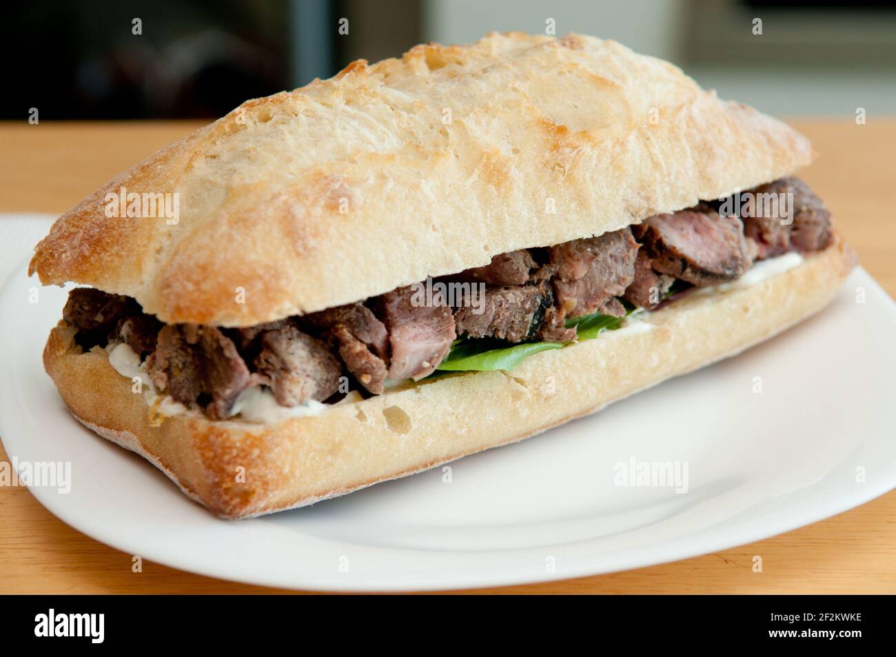 An appetizing sandwich with ciabatta bread, beef, lettuce, and sauce ...
