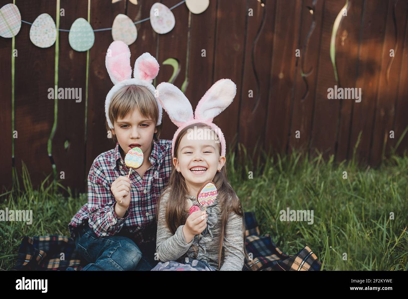 Easter celebration. Little girl and boy eat gingerbread cookie in shape ...