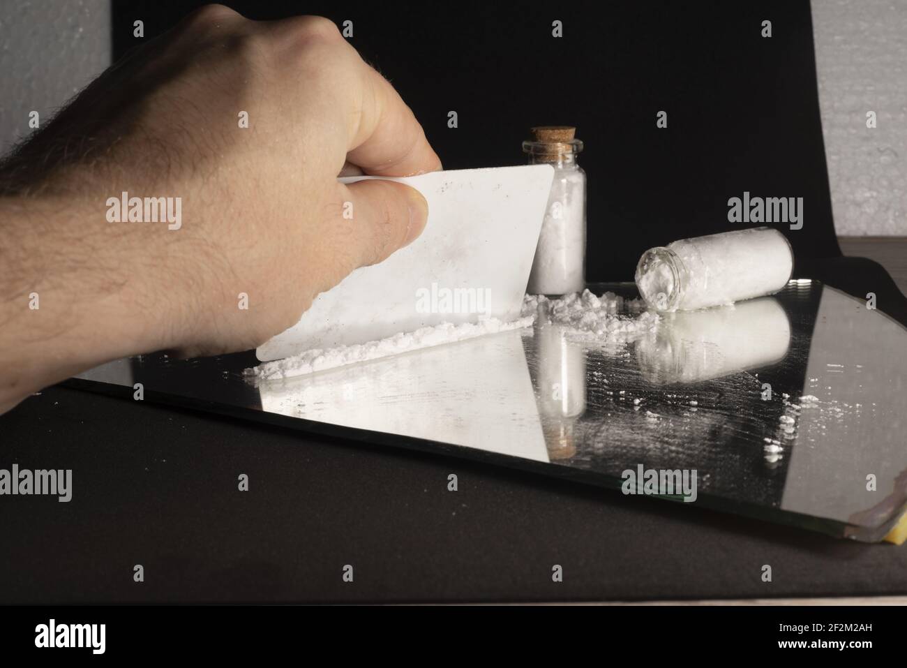 A person making thin cocaine lines with a card on a mirror - drug ...