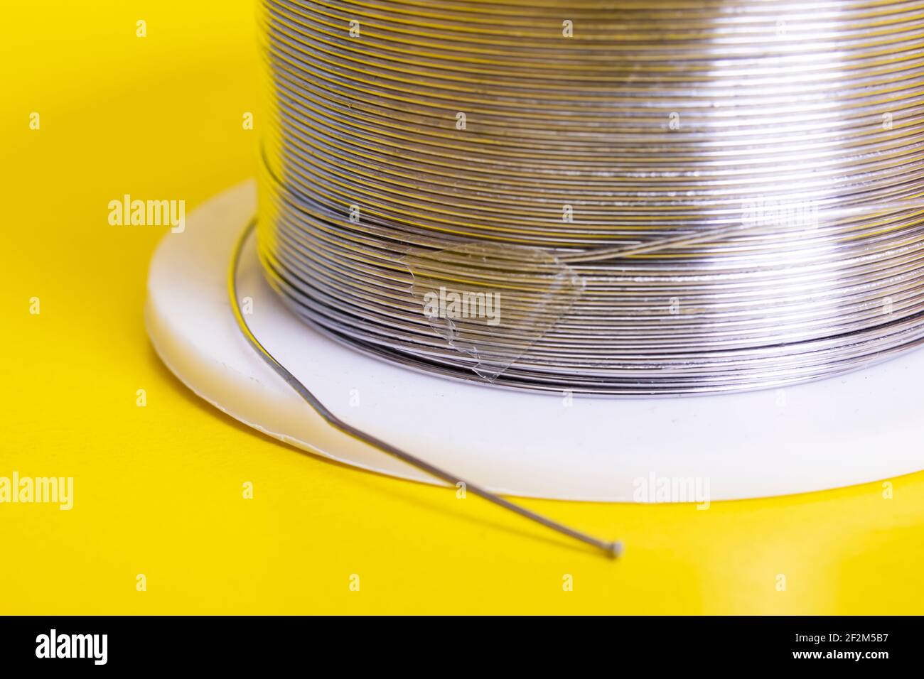 Metal wire spool on a yellow background close up Stock Photo - Alamy
