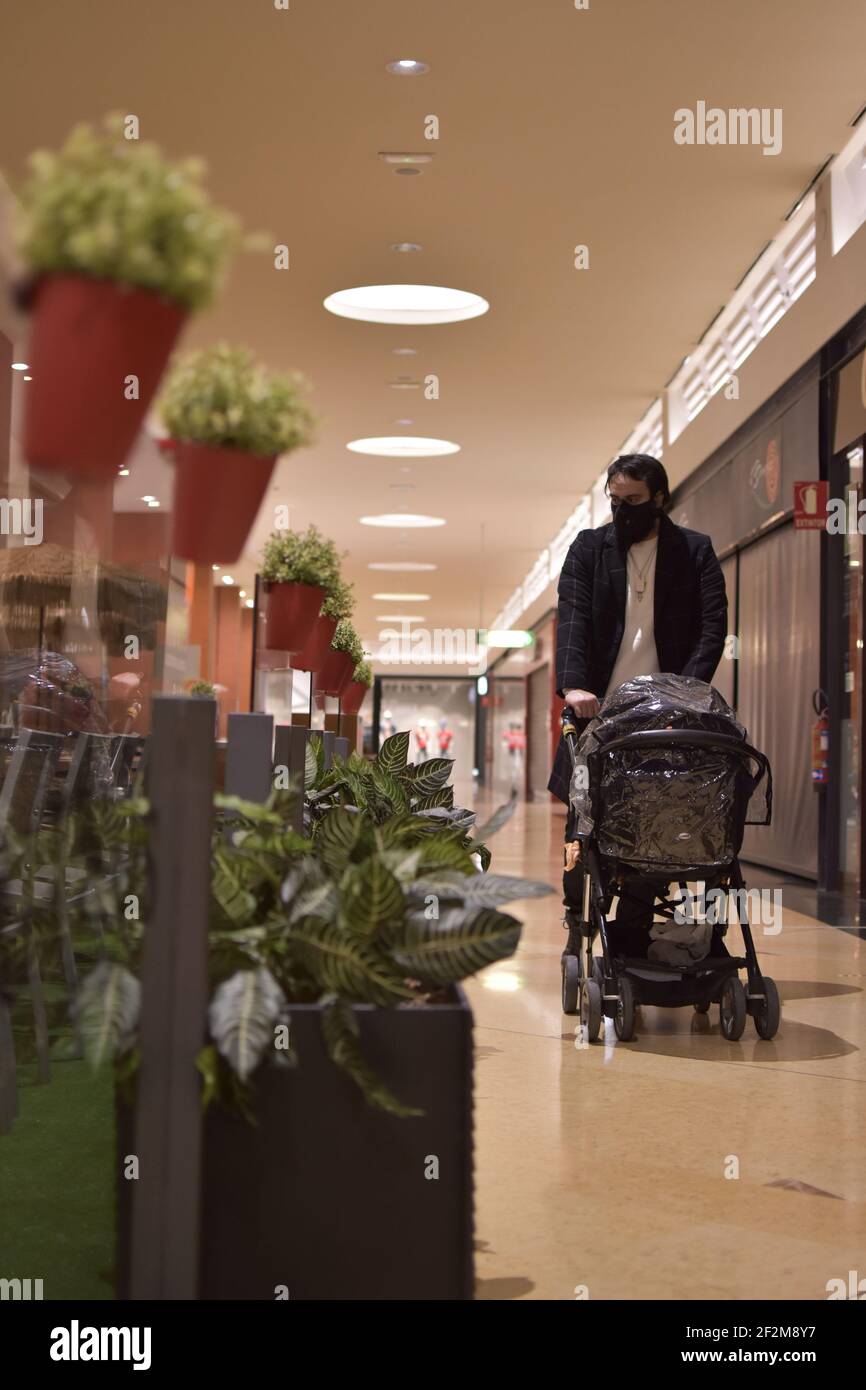 Single dad walking with a baby` stroller in a mall in coronavirus time ...
