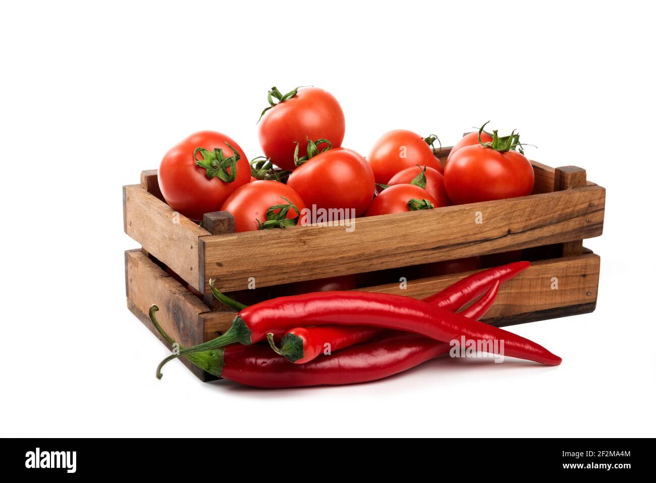 A wooden old box full of fresh juicy red tomatoes with red hot chili ...