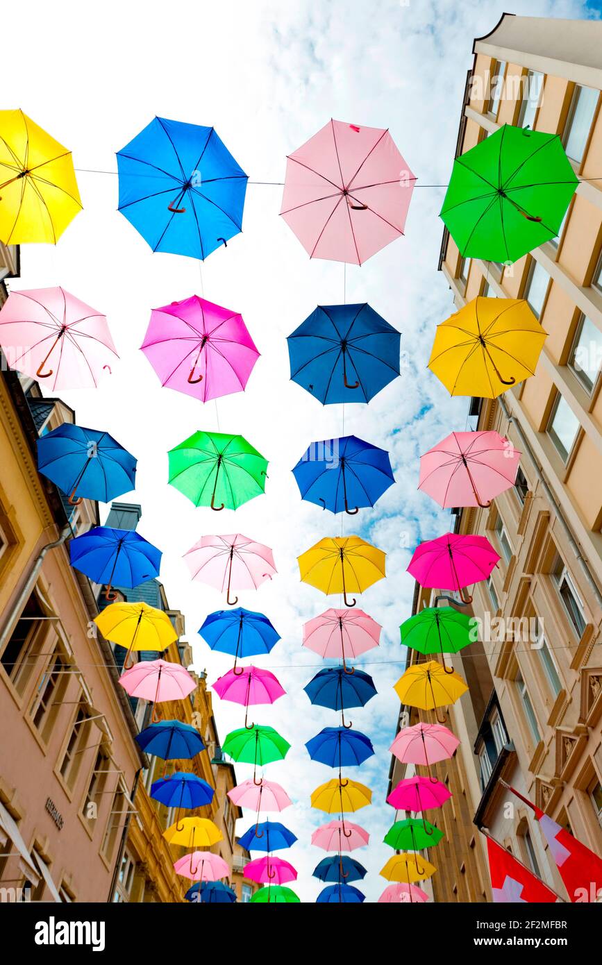 Colorful umbrellas hanging between the houses in a pedestrian zone ...