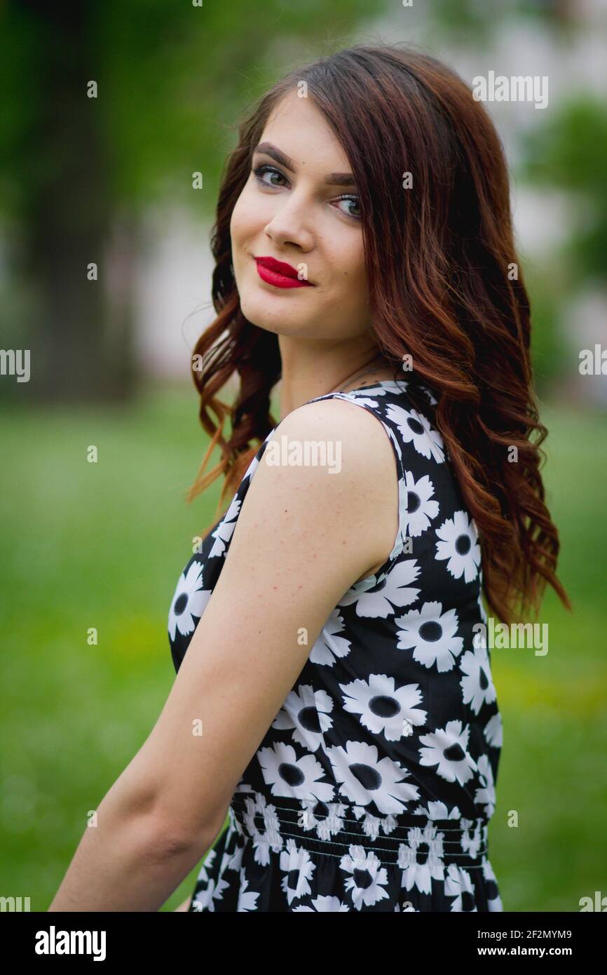A shallow focus of a happy brunette woman wearing a floral dress in a ...