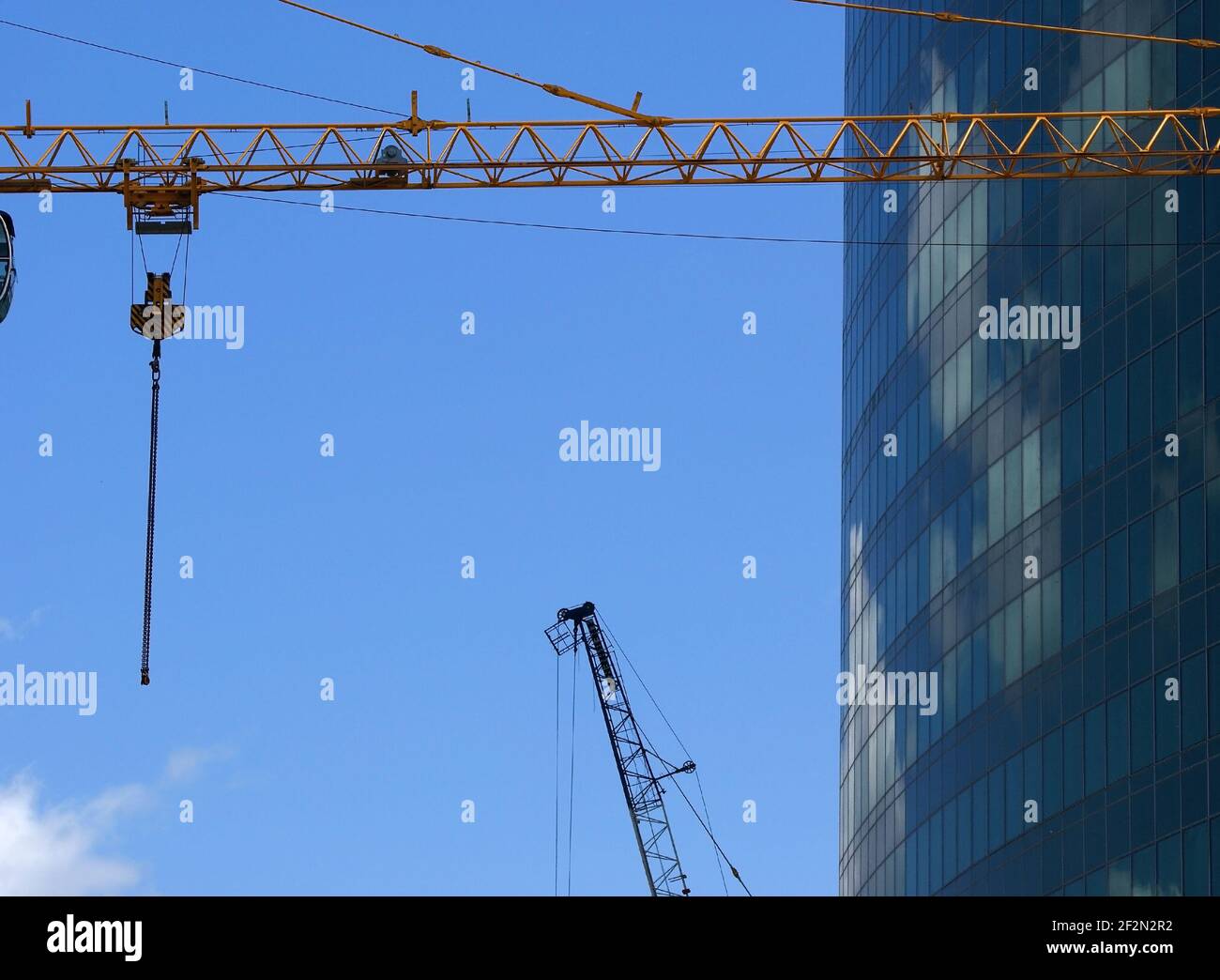 Construction crane at the windows of a skyscraper backdrop of glass and ...