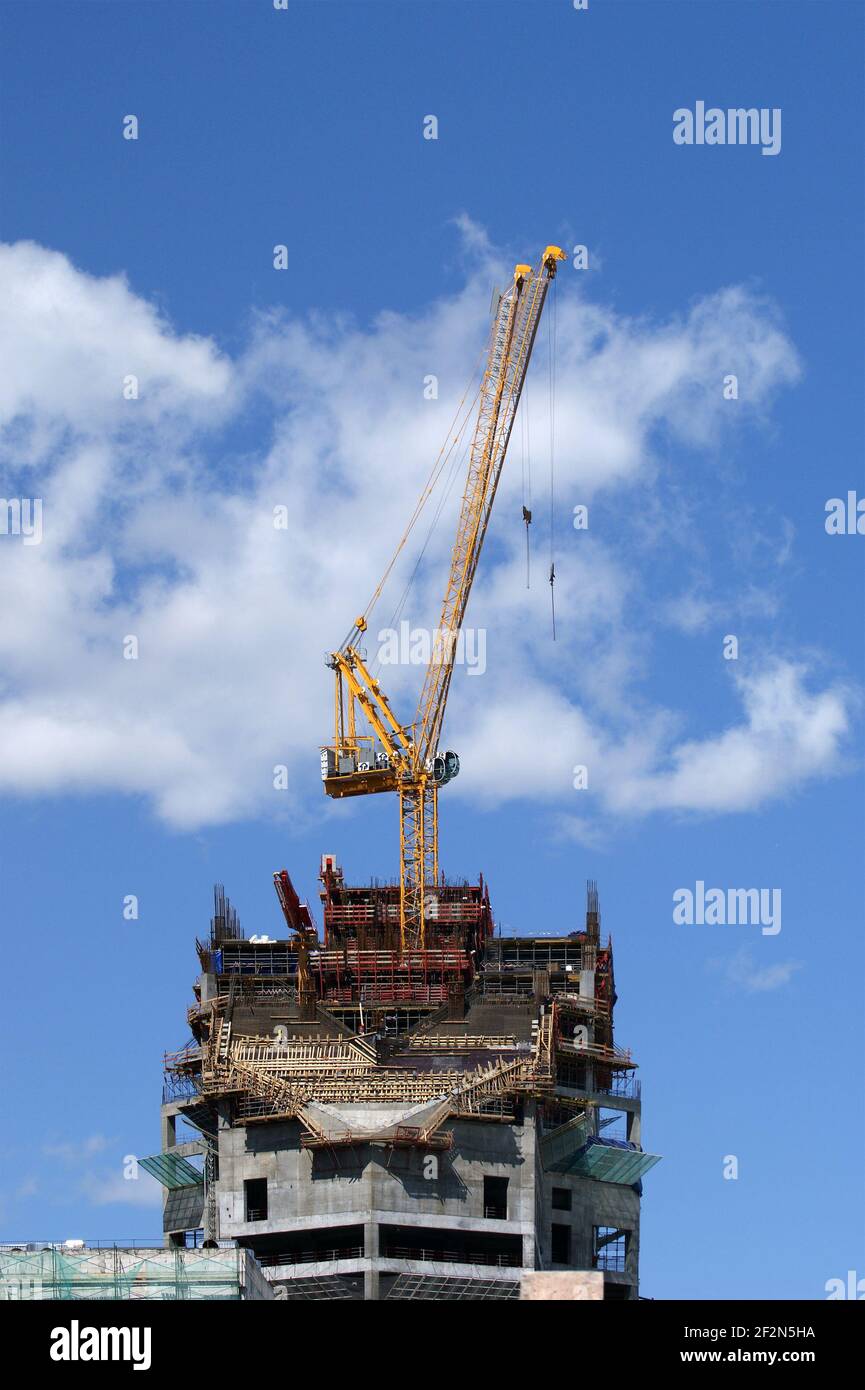 Construction crane at the windows of a skyscraper backdrop of glass and ...