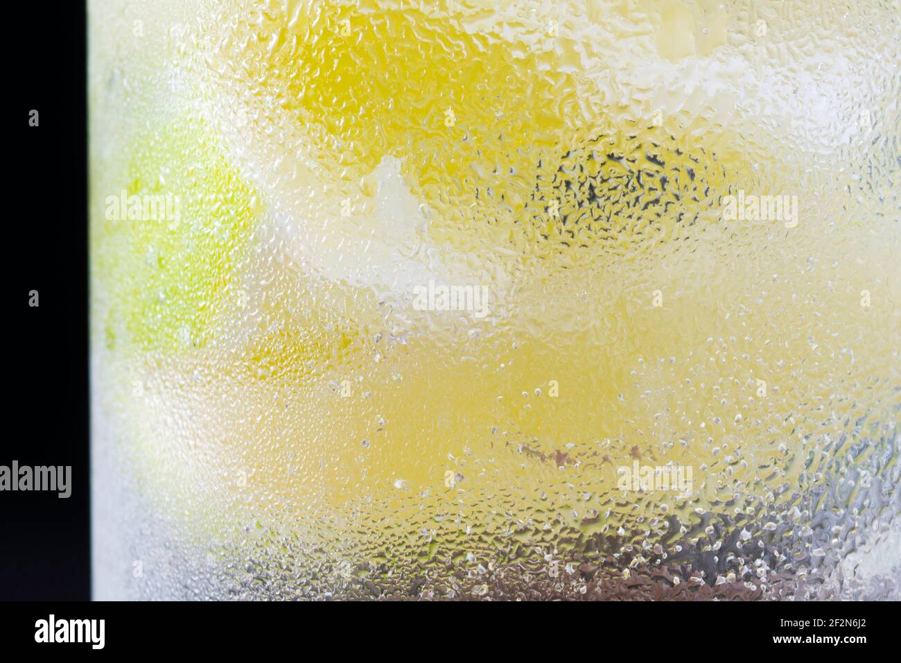 a slice of lime fruit in a fizzy sparkling water, on a black background ...