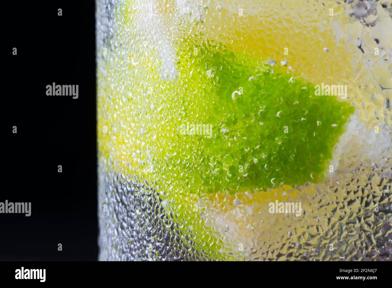 a slice of lime fruit in a fizzy sparkling water, on a black background ...