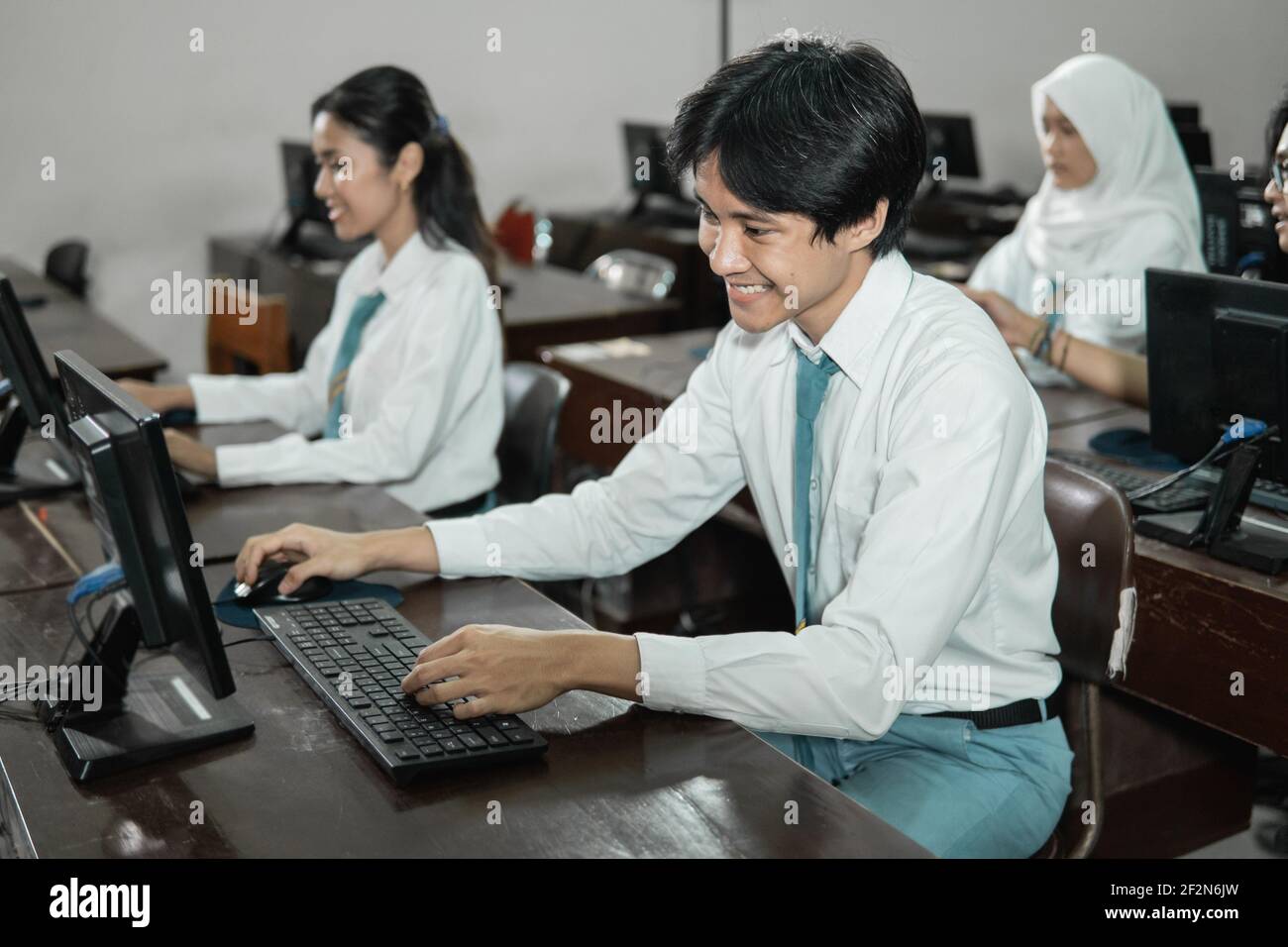 Indonesian high school students smile while using a computer pc with ...
