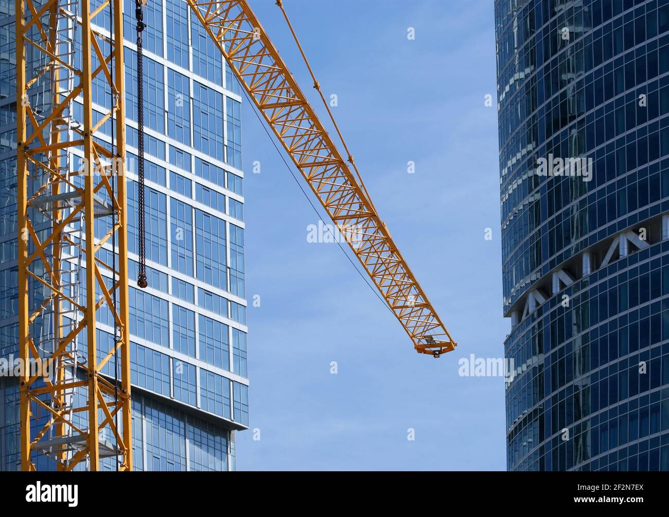 Construction crane at the windows of a skyscraper backdrop of glass and ...