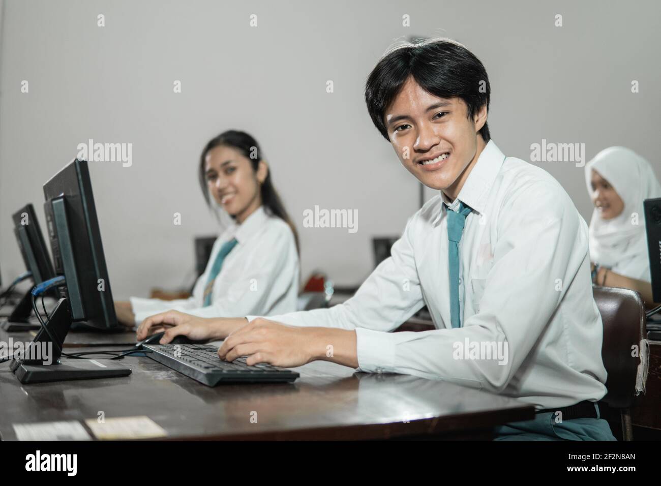 Male high school students smile looking at the camera while using a ...