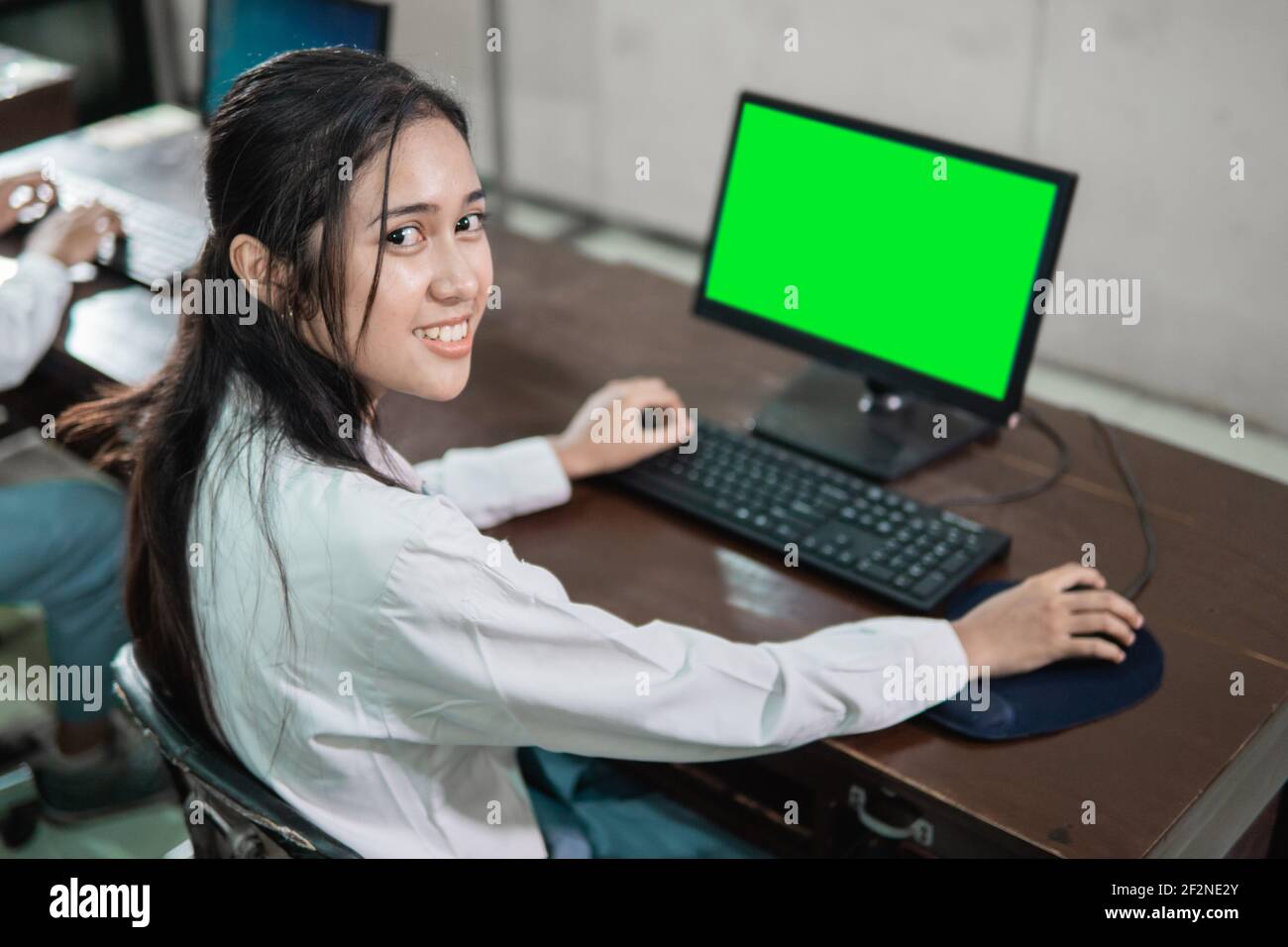 close up of a female student smiling with a look back while using a ...
