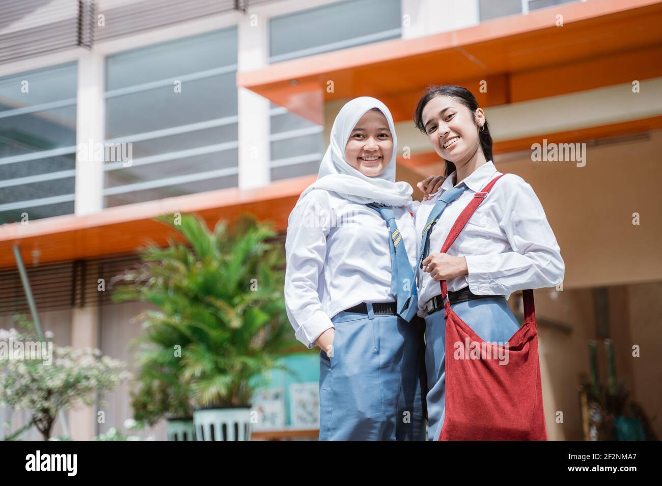 two beautiful student wearing an Indonesian high school uniform and bag ...