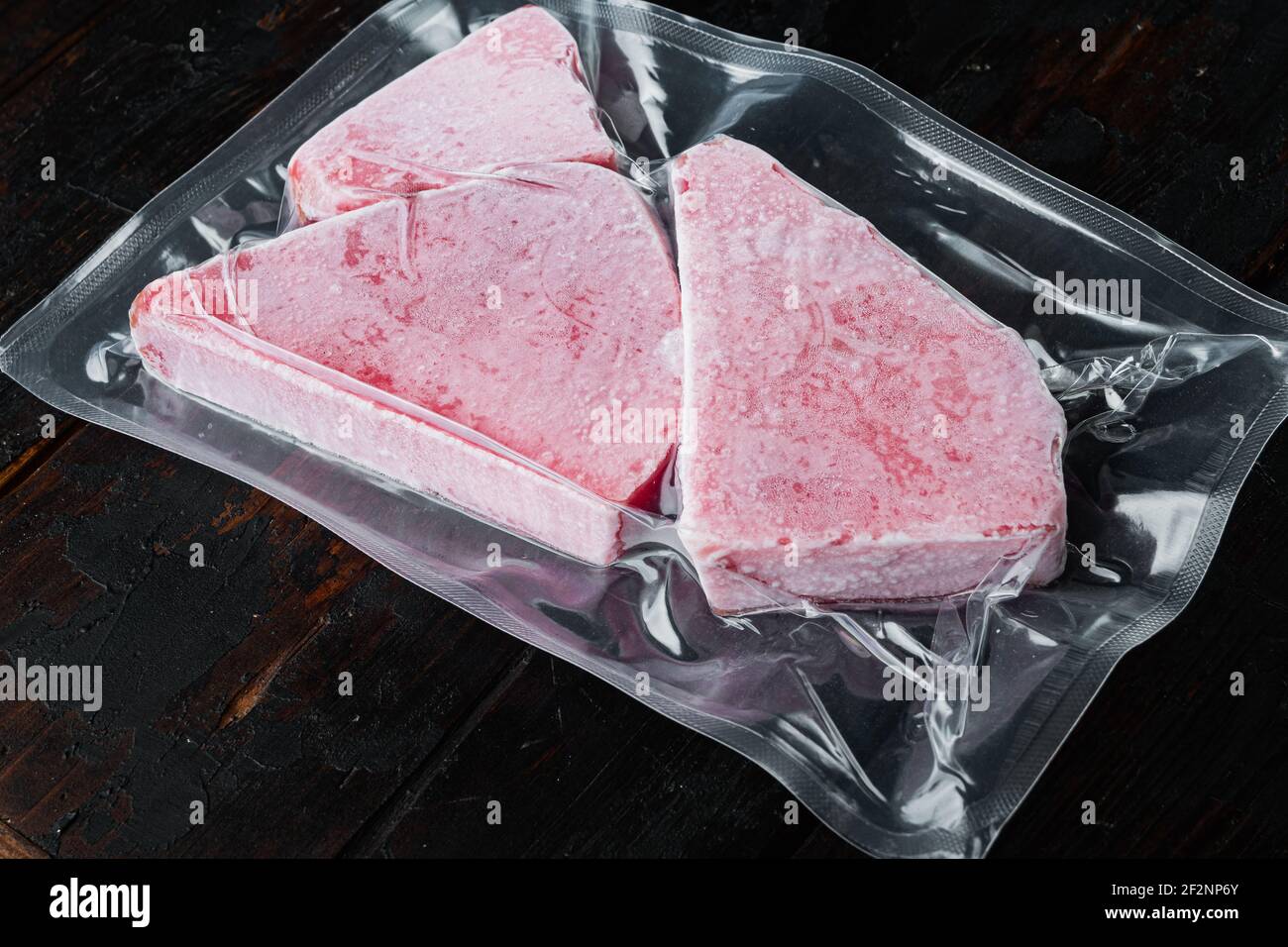 Raw frozen tuna fillet in vacuum packaging set, on old dark wooden ...