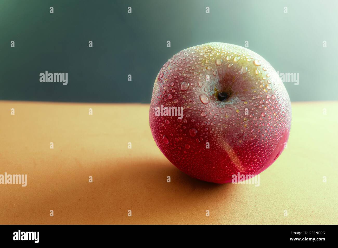 A close-up shot of one fresh whole red apple on the yellow surface and ...