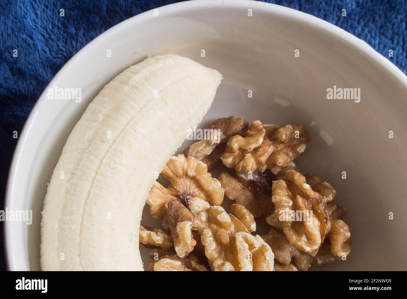 A handful of walnuts and half a peeled banana on a plate. Healthy ...