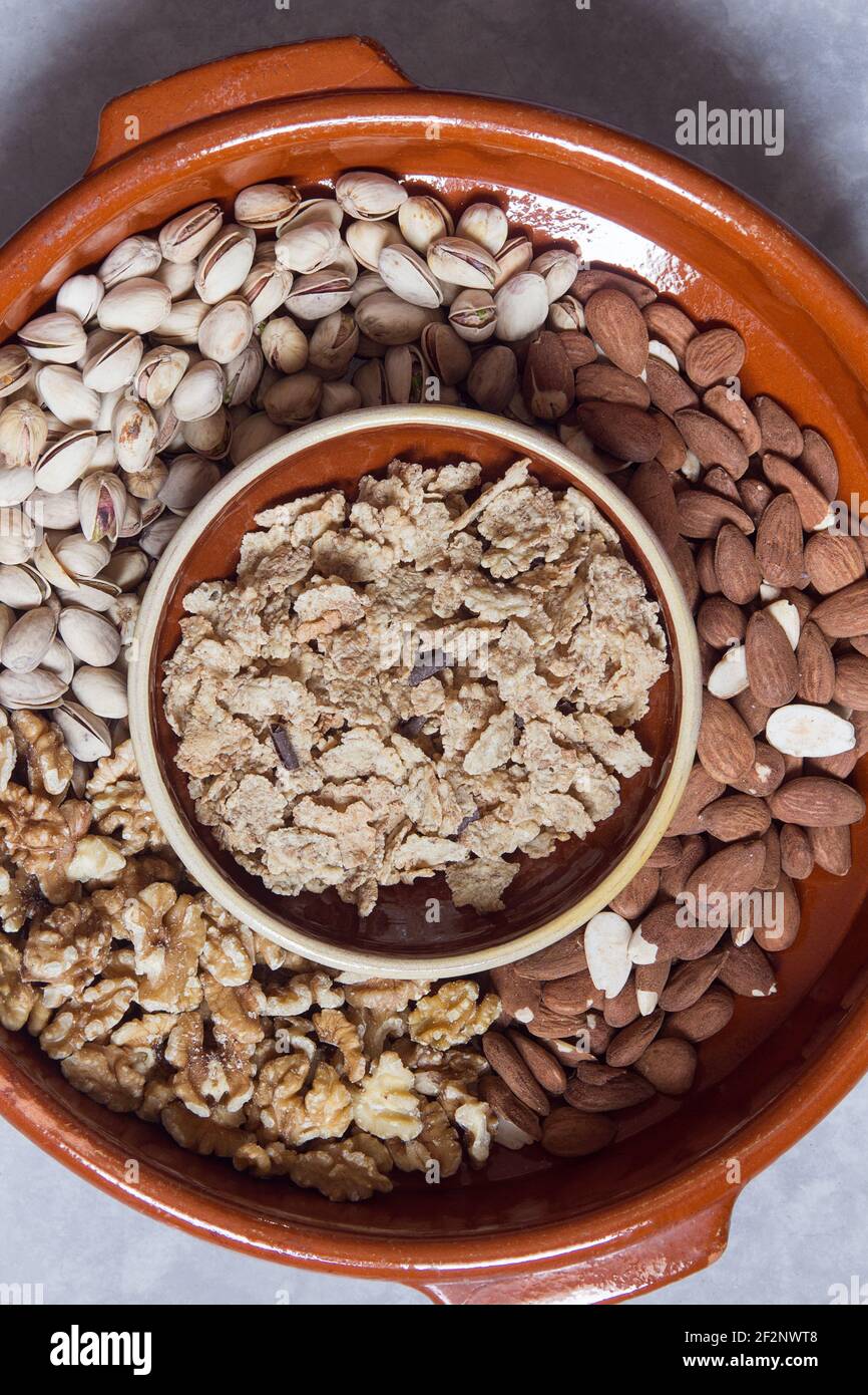 An old earthenware pot filled with mixed dried fruits with a clay bowl ...