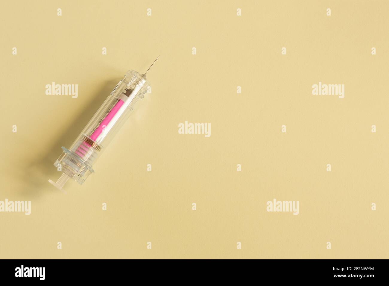 A colorful isolated pink syringe with the needle uncapped on textured ...