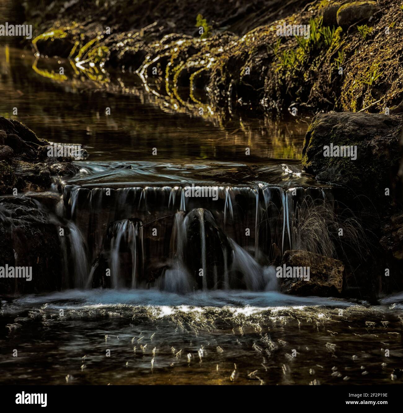 Intimate landscape of stream rushing over a waterfall in a woodland ...