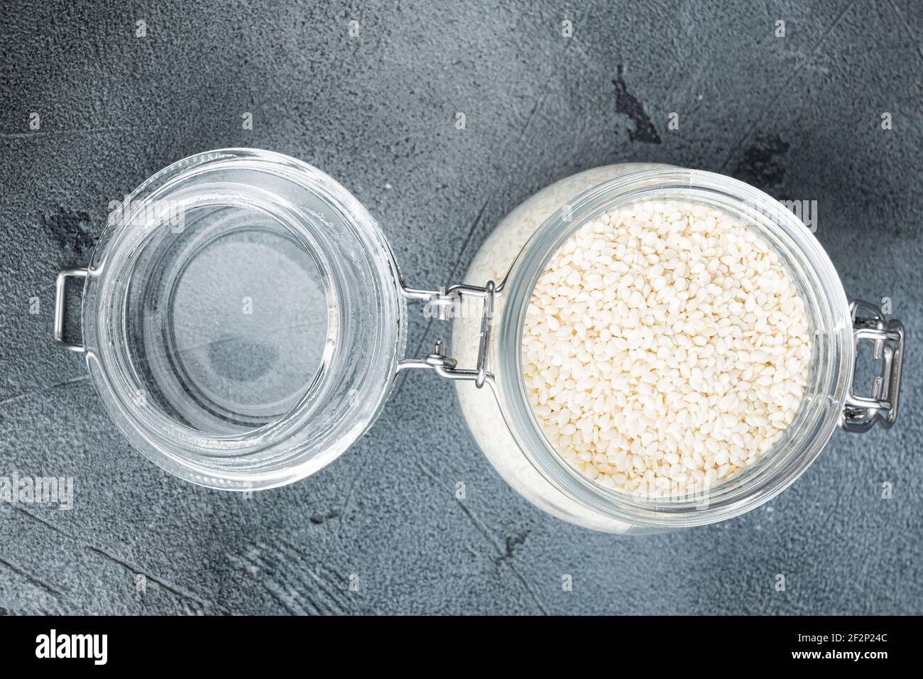 Decorticated sesame seeds set, in glass jar, on gray stone background ...
