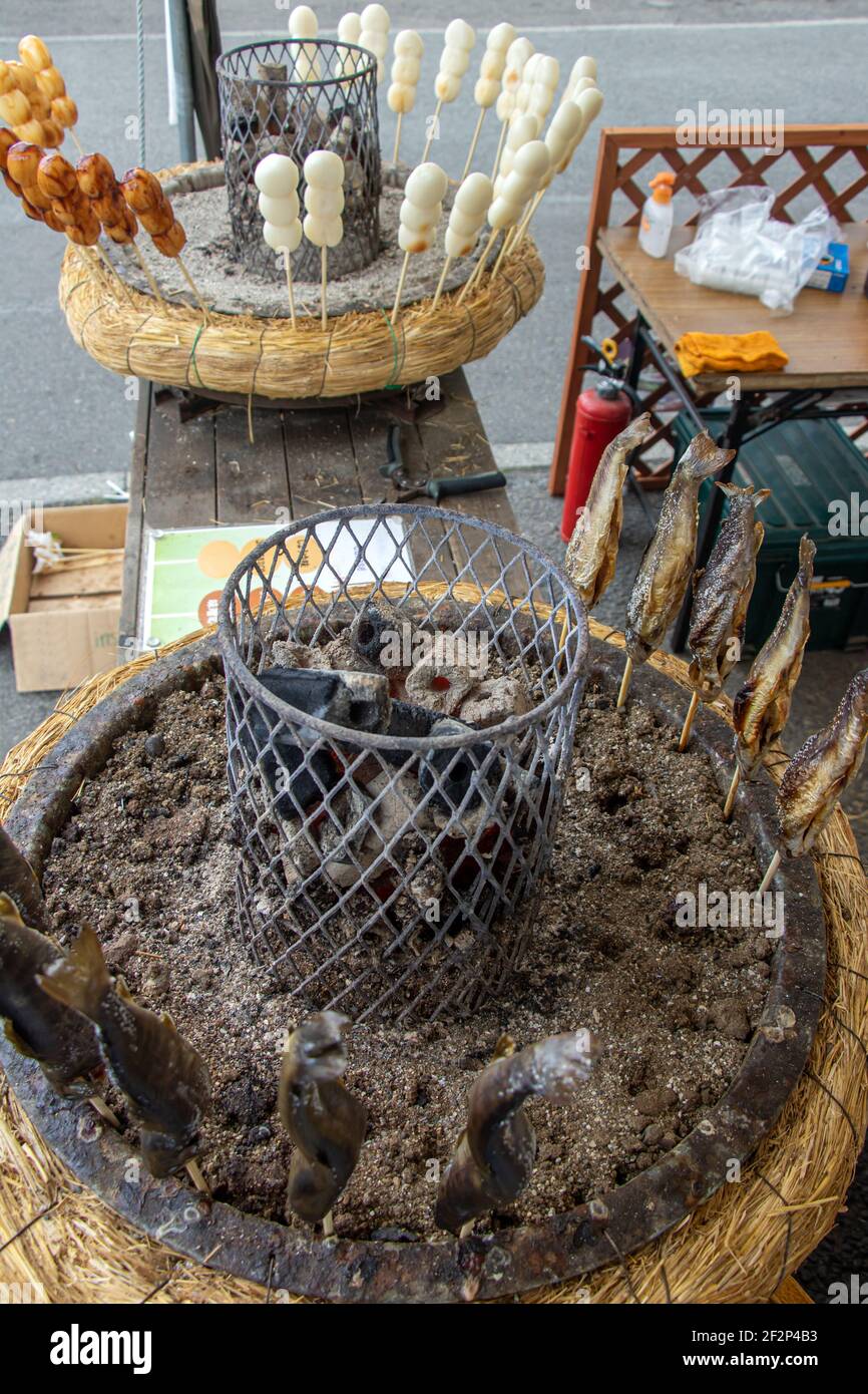 Roasted fish on a sticks around heating coal. Sales of fresh baked fish ...