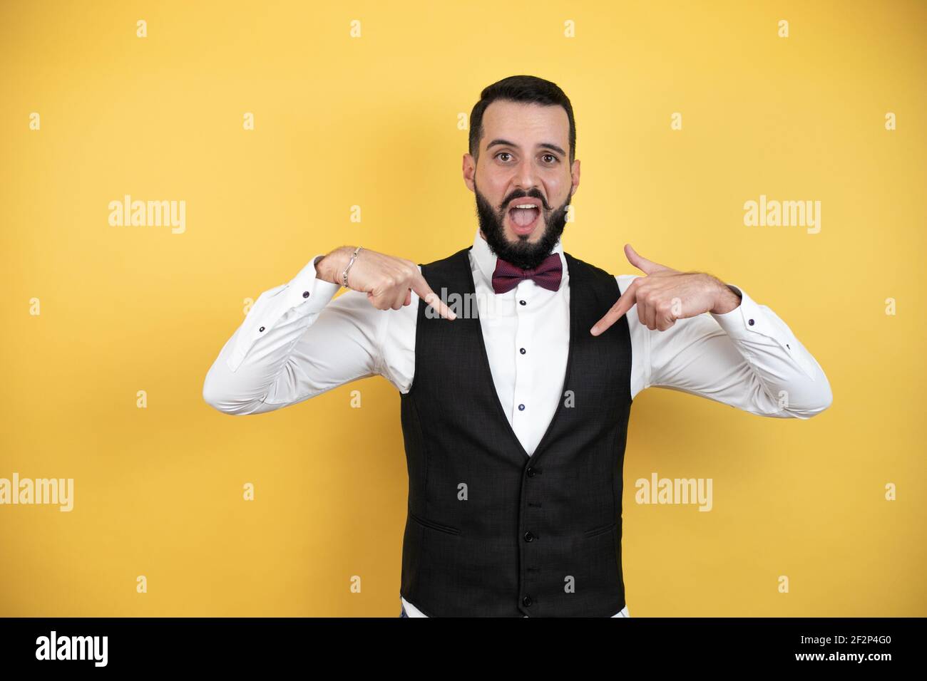 Young man with beard wearing bow tie and vest looking confident with ...