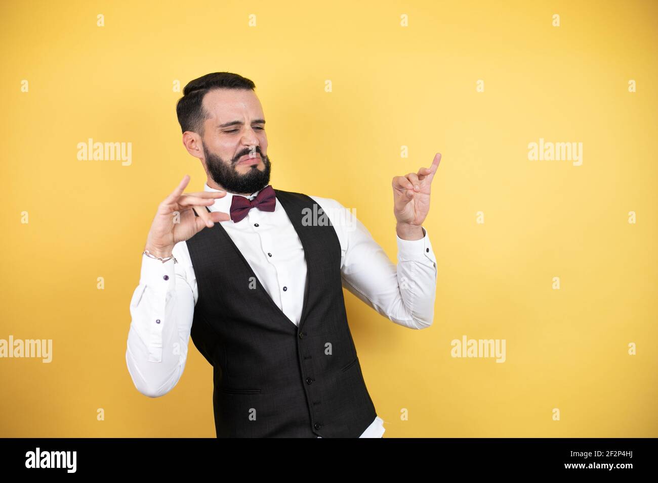 Young man with beard wearing bow tie and vest disgusted expression ...