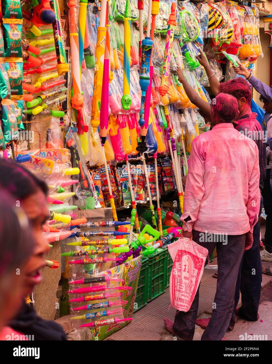 India Vrindavan Men covered in colored powder shopping for water guns ...
