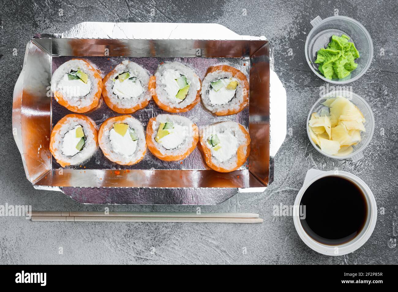 Tasty sushi rolls in disposable boxes set, on gray stone background ...