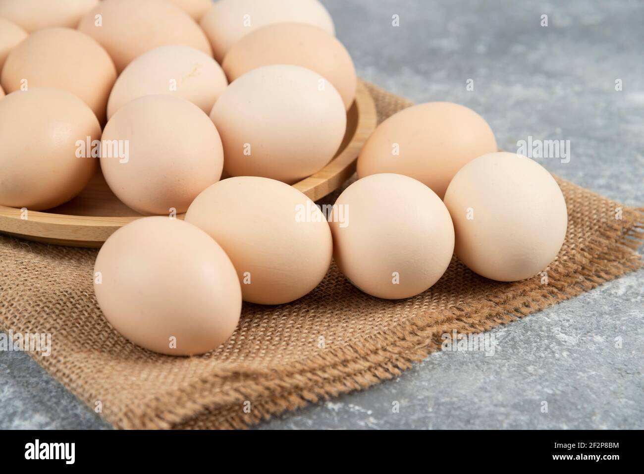 Wooden plate of organic uncooked eggs on marble surface Stock Photo - Alamy