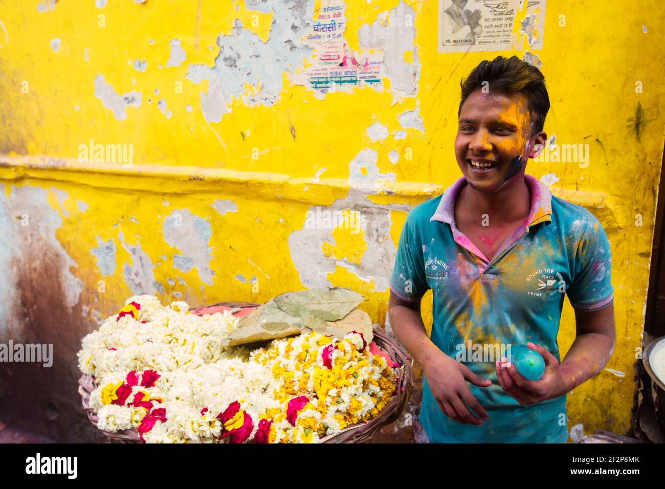 India Vrindavan Young man covered in colored powder selling flowers ...