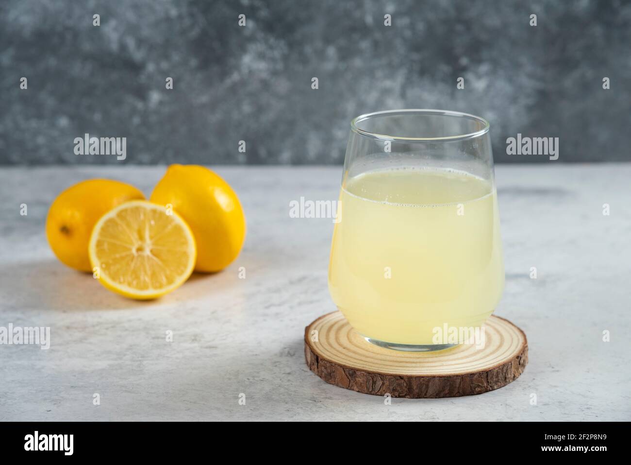 A glass cup of fresh lemon juice on a wooden board Stock Photo - Alamy
