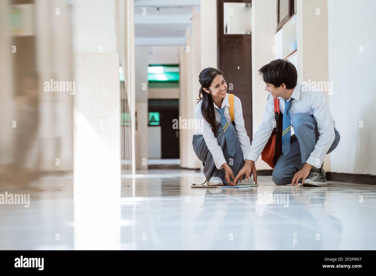 a boy and a girl in Indonesian high school uniform pick up the book ...