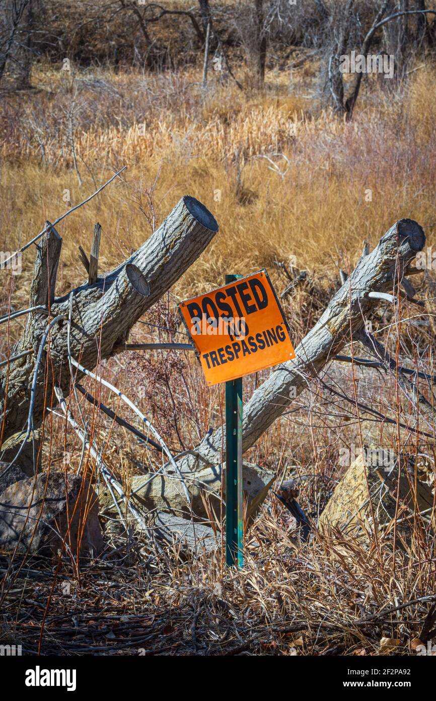 Bent no trespassing sign on metal post is framed by cut sections of ...