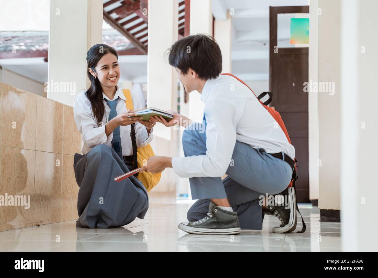 a boy and a girl in Indonesian high school uniform pick up the book ...