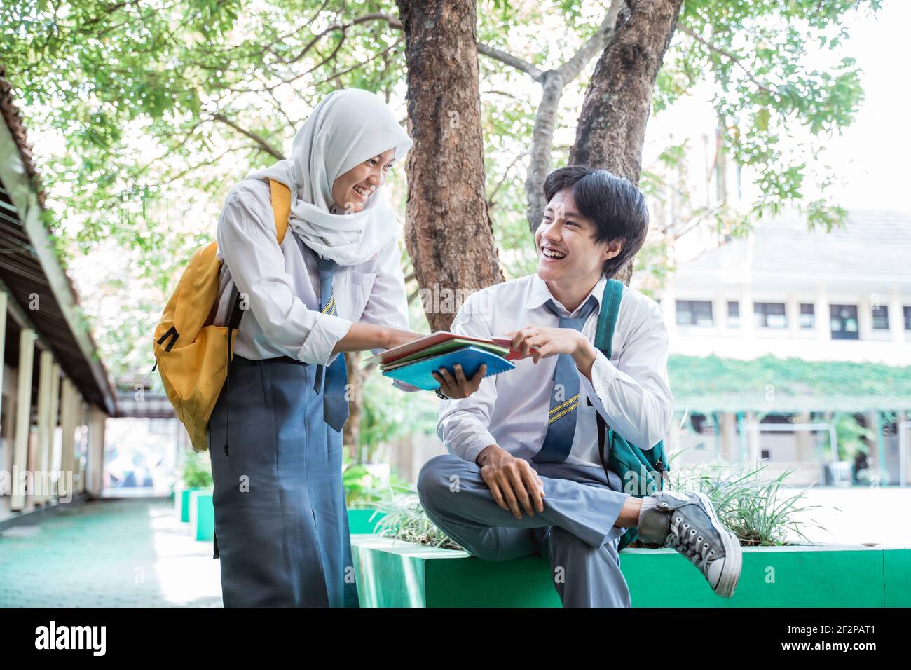 a smiling boy and veiled girl in Indonesian high school uniform chat ...
