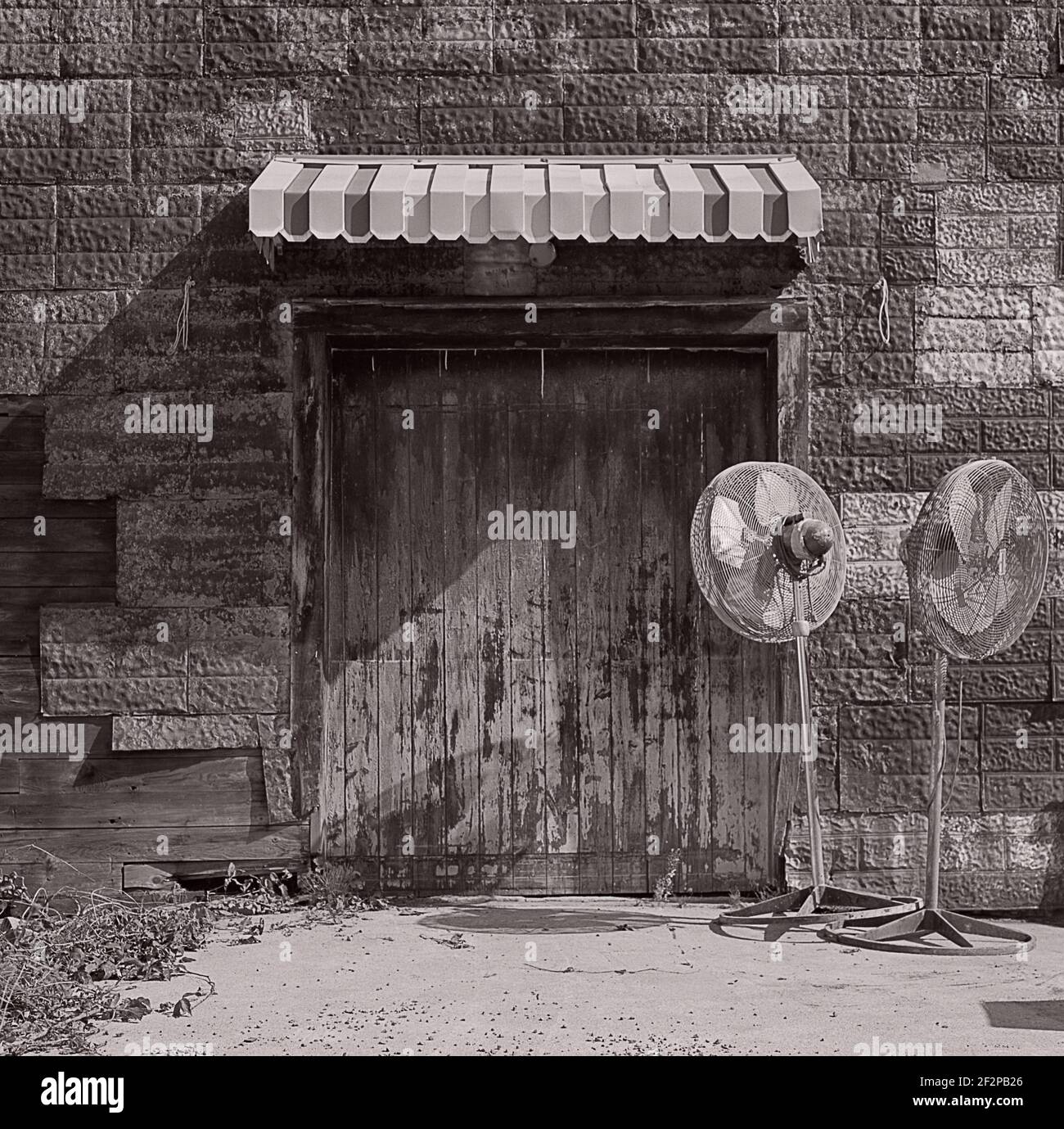 Two abandoned, electric fans left in front of an old building door with ...