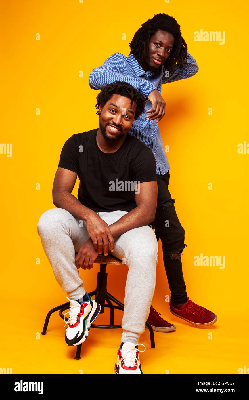 two african american guys posing cheerful together on yellow background ...