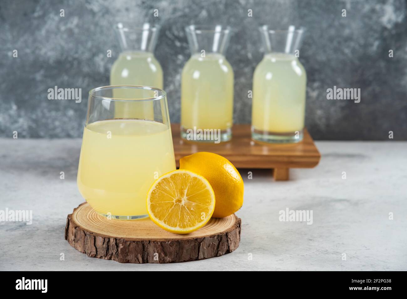 A glass cup of fresh lemon juice on a wooden board Stock Photo - Alamy