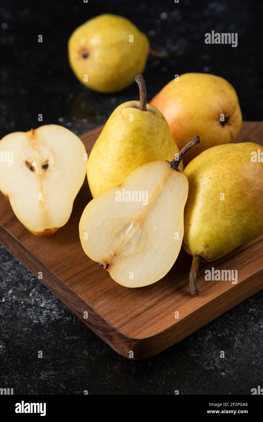Wooden board of delicious yellow pears on black surface Stock Photo - Alamy