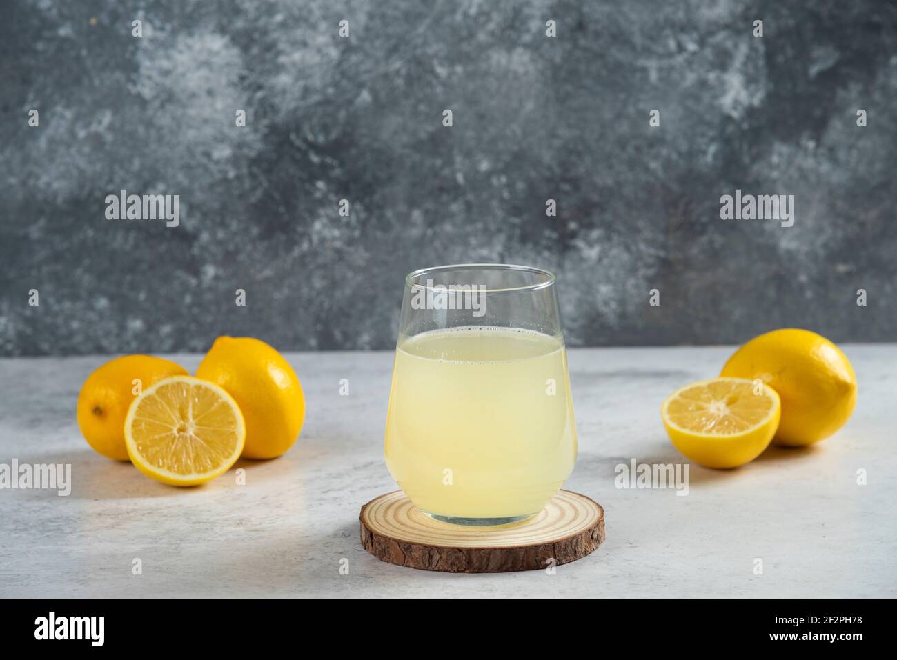 A glass cup of fresh lemon juice on a wooden board Stock Photo - Alamy