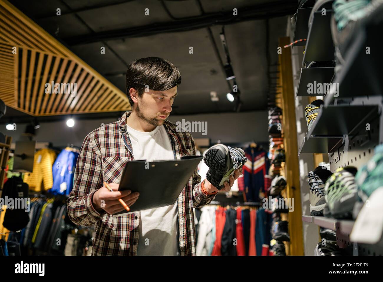 Sporting goods store owner with clipboard checking inventory. Tourist ...
