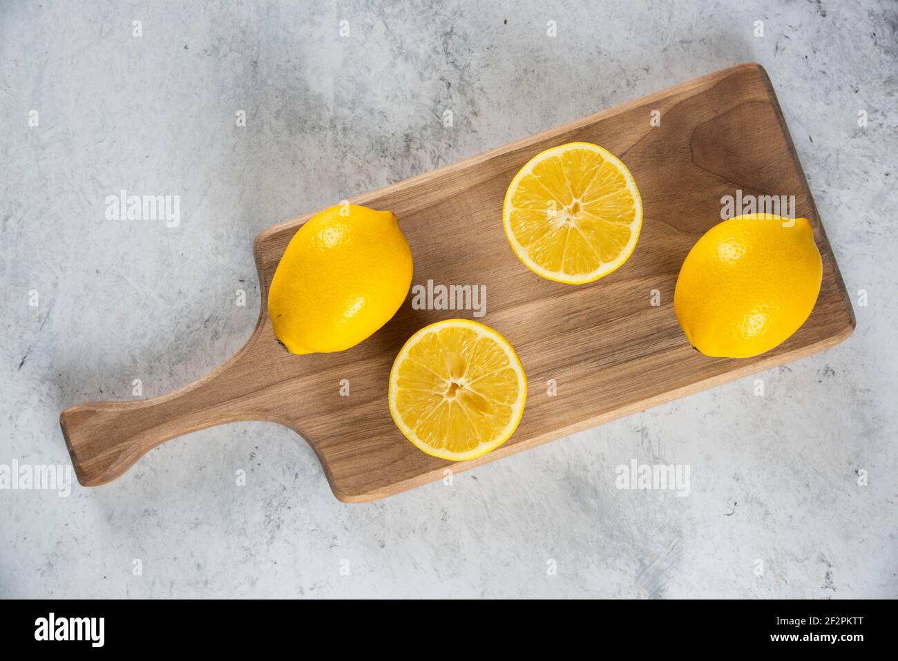 Sliced and whole lemons with wooden reamer Stock Photo - Alamy