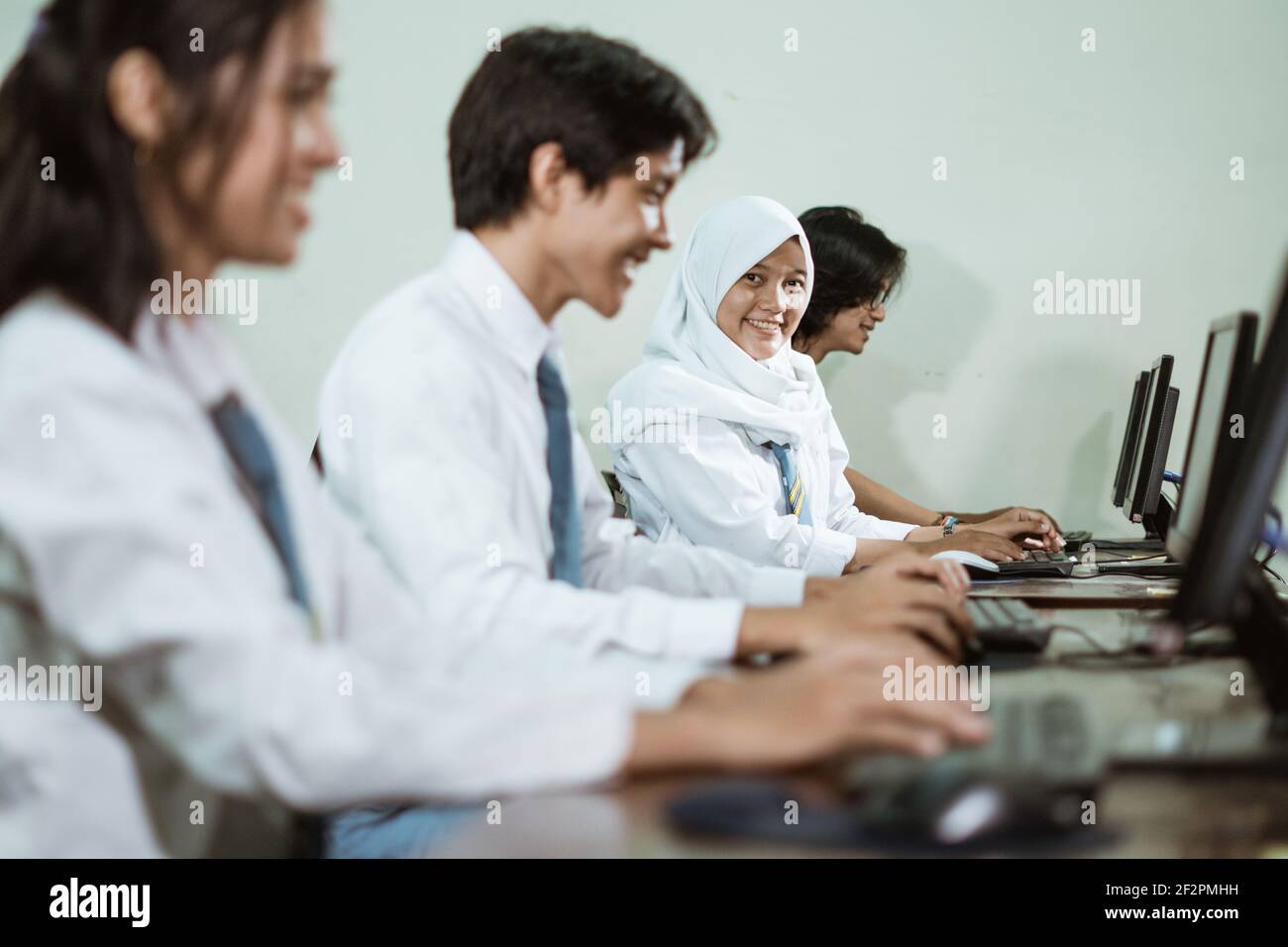 Indonesian high school students using computer pc with their friends ...
