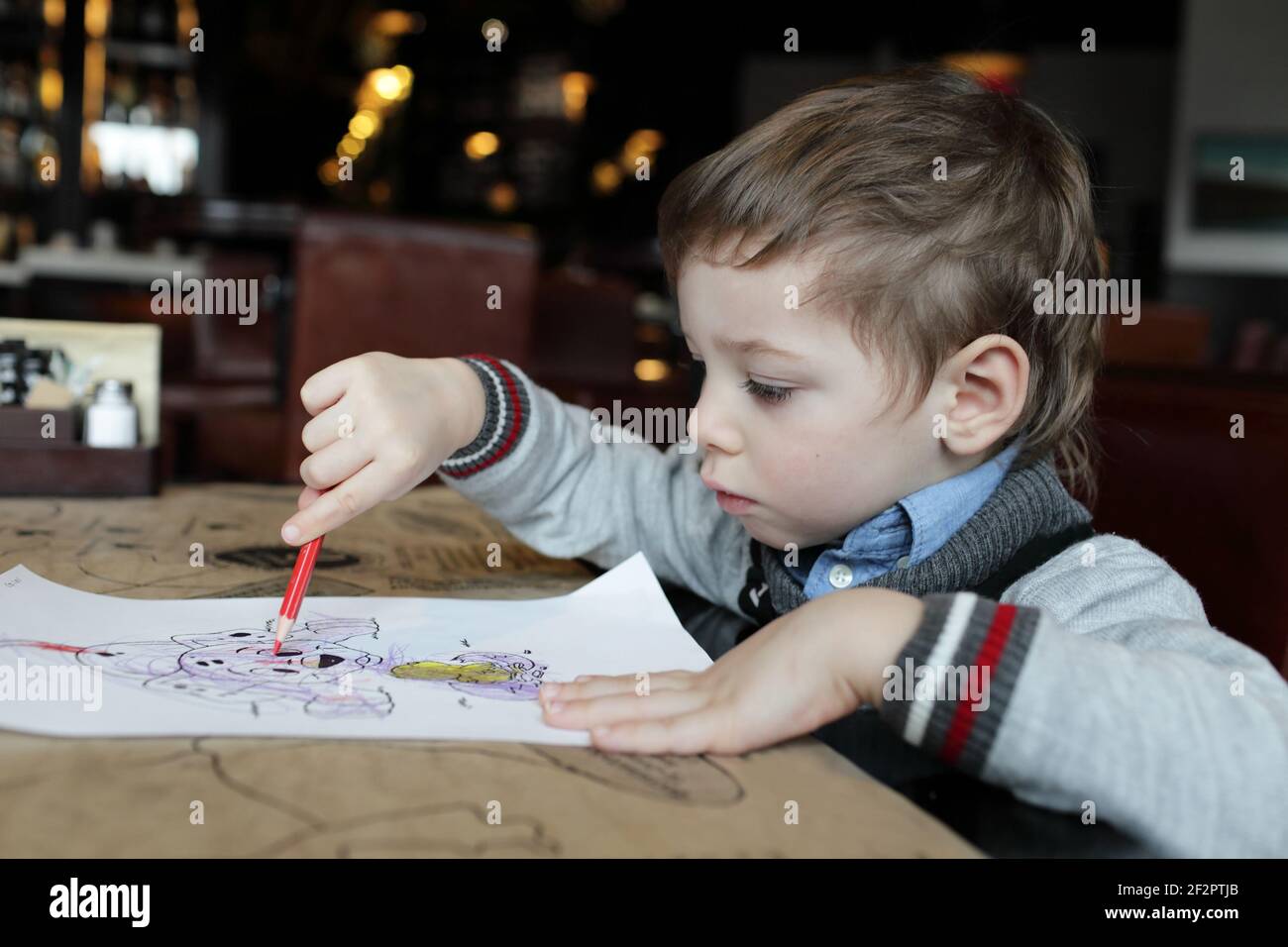 The serious child drawing at the cafe Stock Photo - Alamy