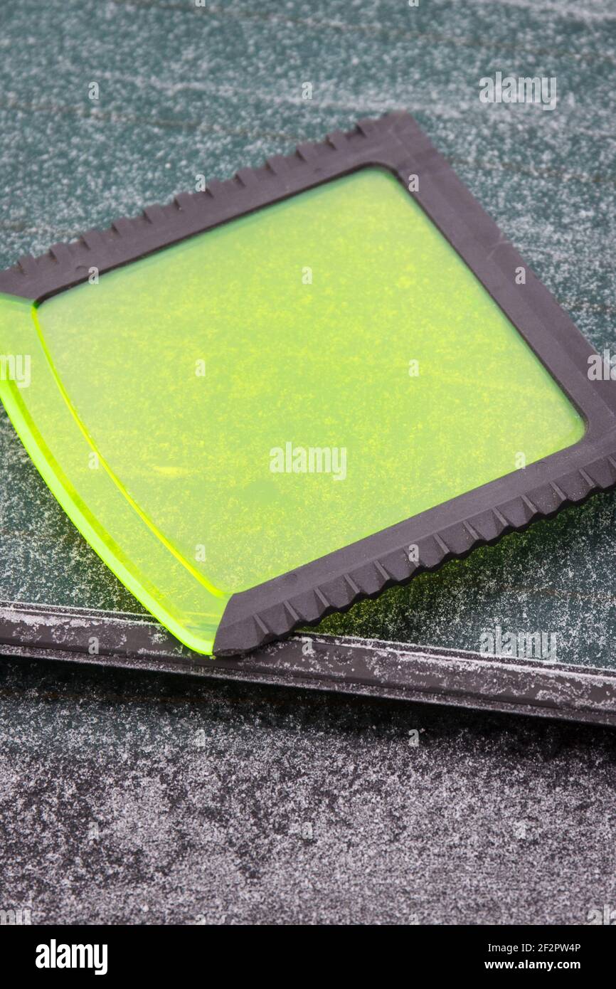 Green ice scraper lying on car windscreen, winter problems in ...
