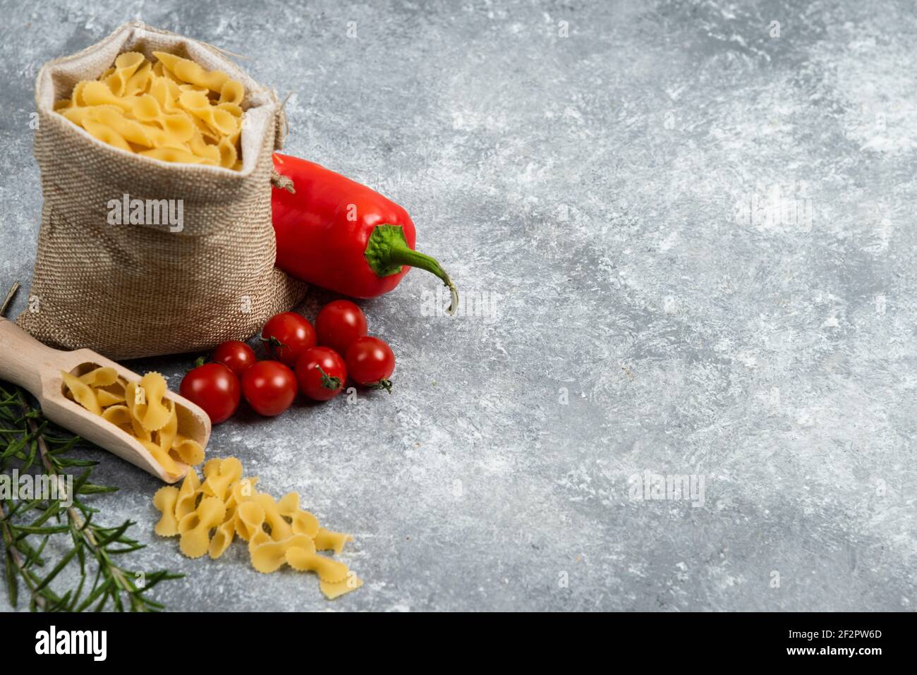 Pasta basket with red chili, tomatoes and rosemary on a marble ...